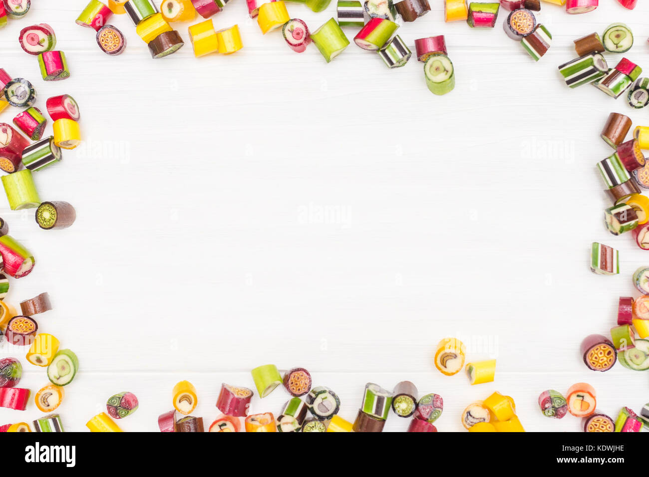 A round frame made of colored caramel candies on white wooden ...