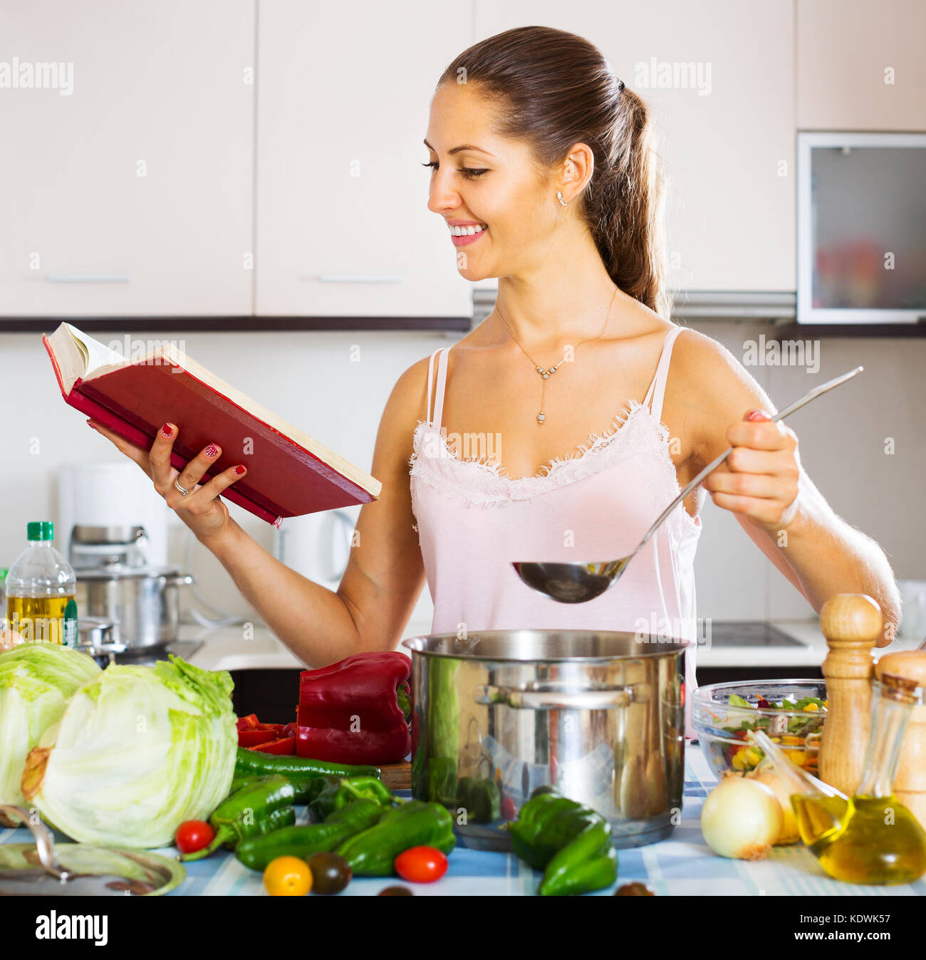 Pretty young girl standing at kitchen table with fresh vegetables Stock ...