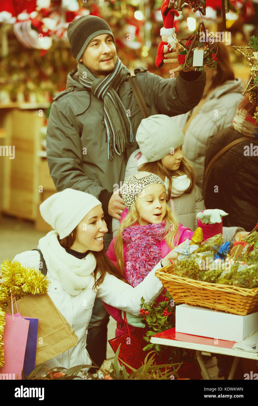 Cheerful young parents with two little daughters buying flower and ...