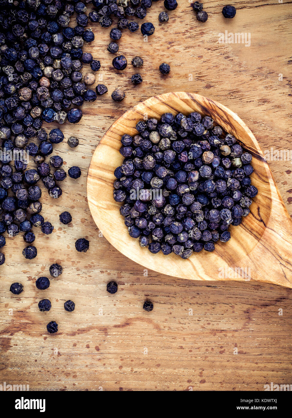 Closeup black pepper in wooden spoon on shabby teak wood table ...