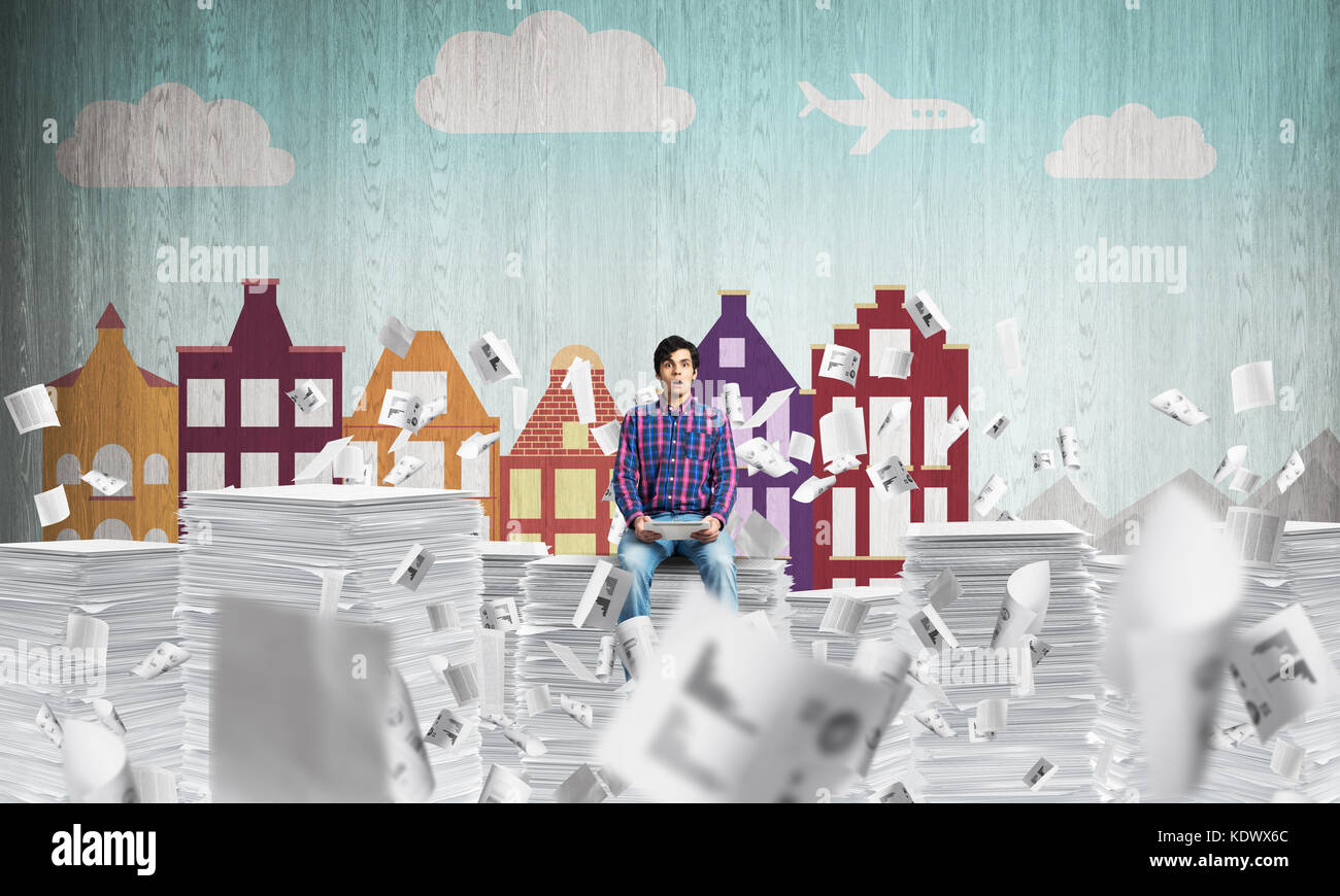Young man sitting on pile of paper documents Stock Photo - Alamy