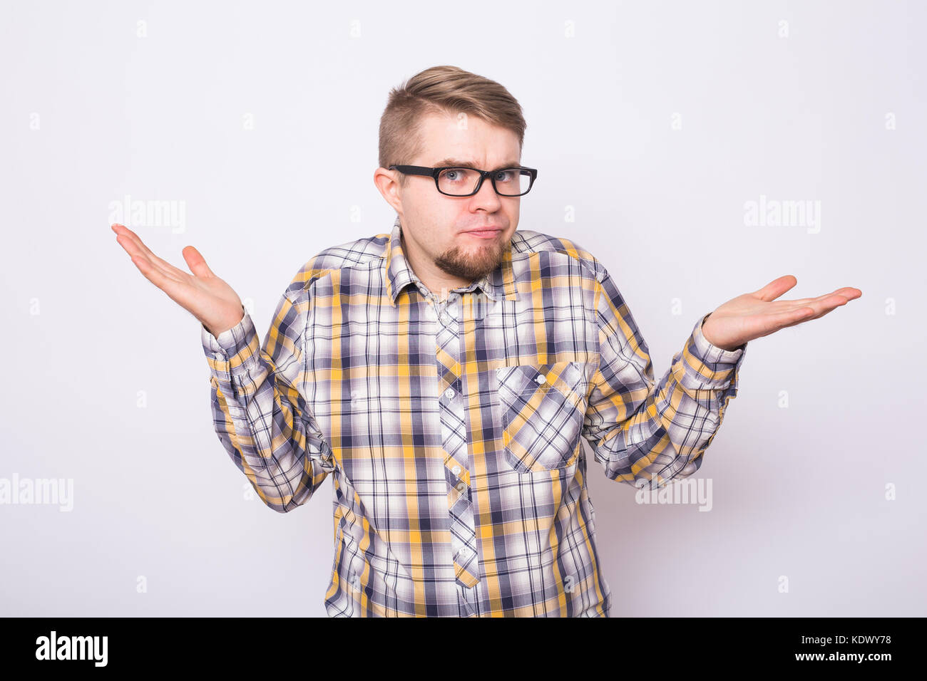 Confused young man dressed in shirt standing over white background ...