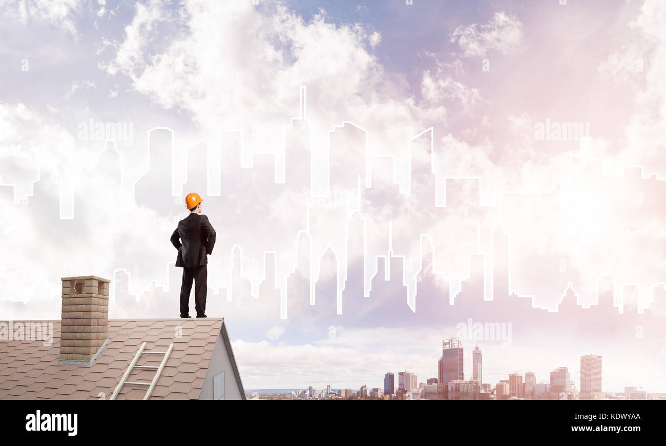Engineer man standing on roof and looking away. Mixed media Stock Photo ...