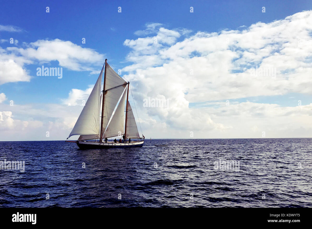 Vintage sail boat sailing on dark blue ocean under blue and cloudy sky ...