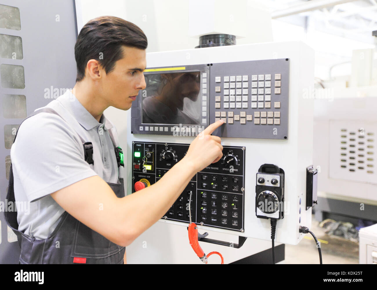 Worker pressing programming buttons on CNC machine control board in ...