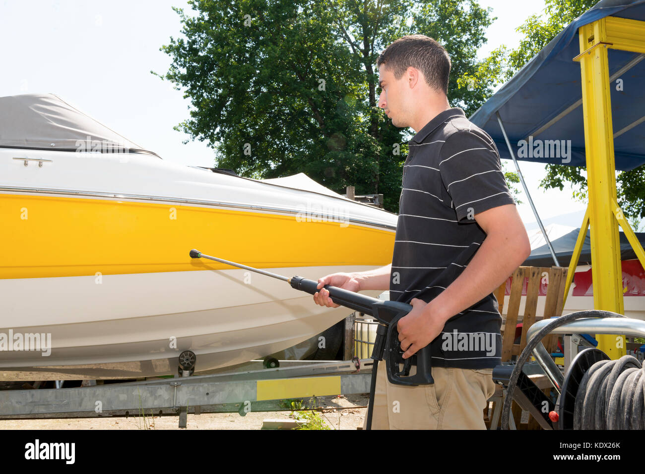 a young man cleaning boat with high pressure water Stock Photo - Alamy
