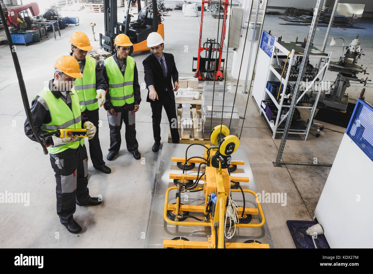 Manager and workers near metal sheet lifting device at factory Stock ...