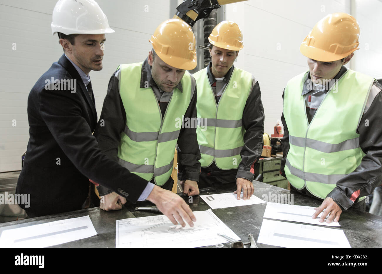 Engineer, foreman and workers wearing safety helmets are meeting at ...
