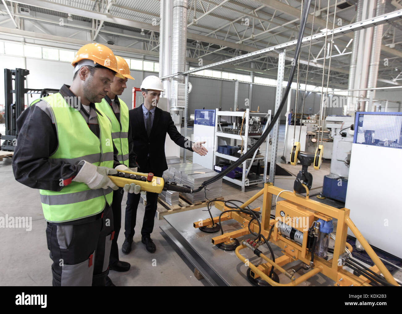 Workers near metal sheet lifting device at factory Stock Photo - Alamy