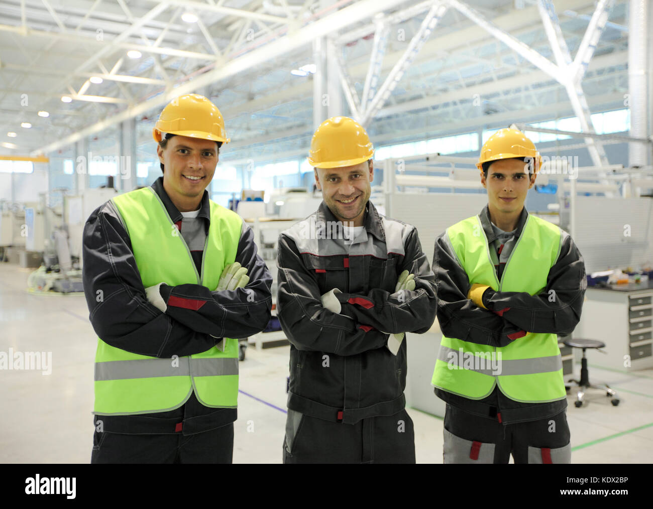 Team of three positive smiling workers in CNC factory Stock Photo - Alamy