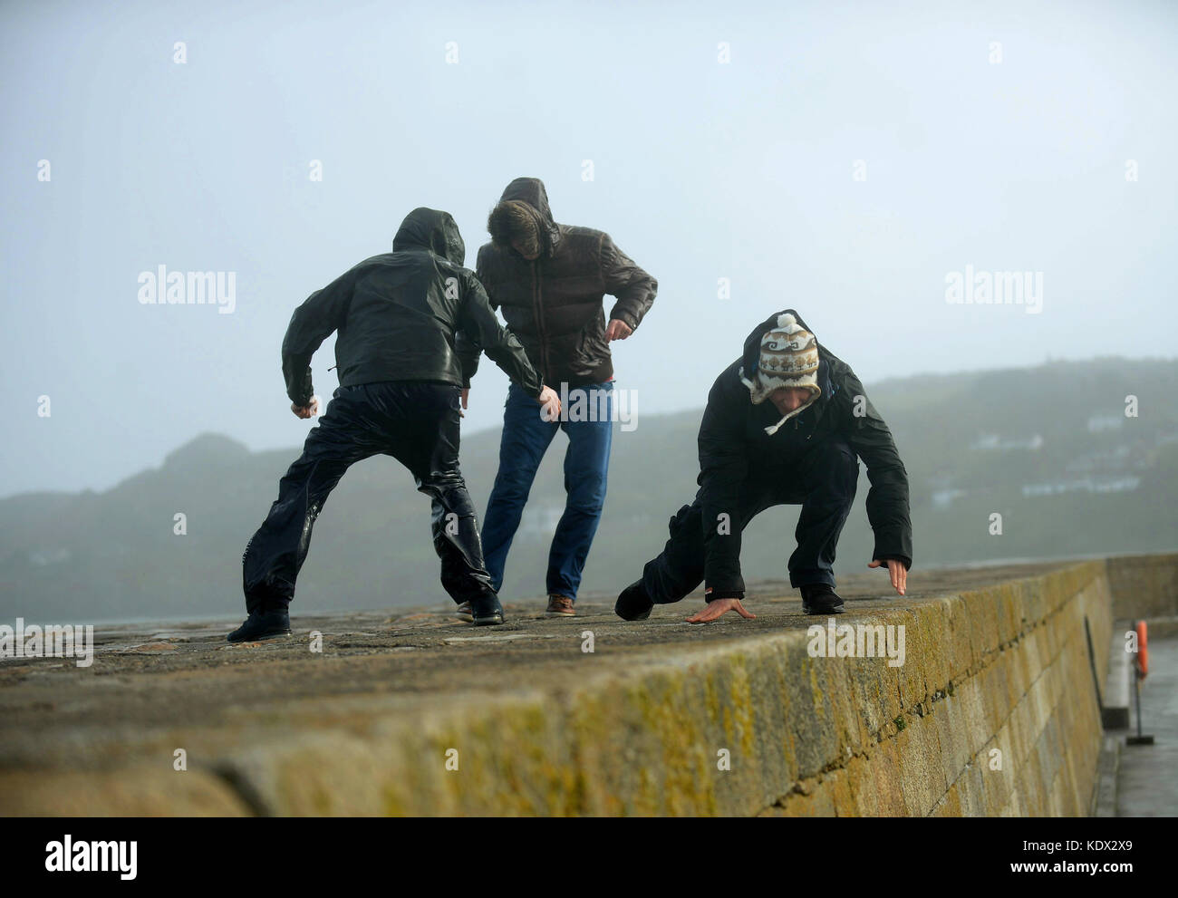 Men struggle to keep their footing amid gusts during storm Ophelia on ...