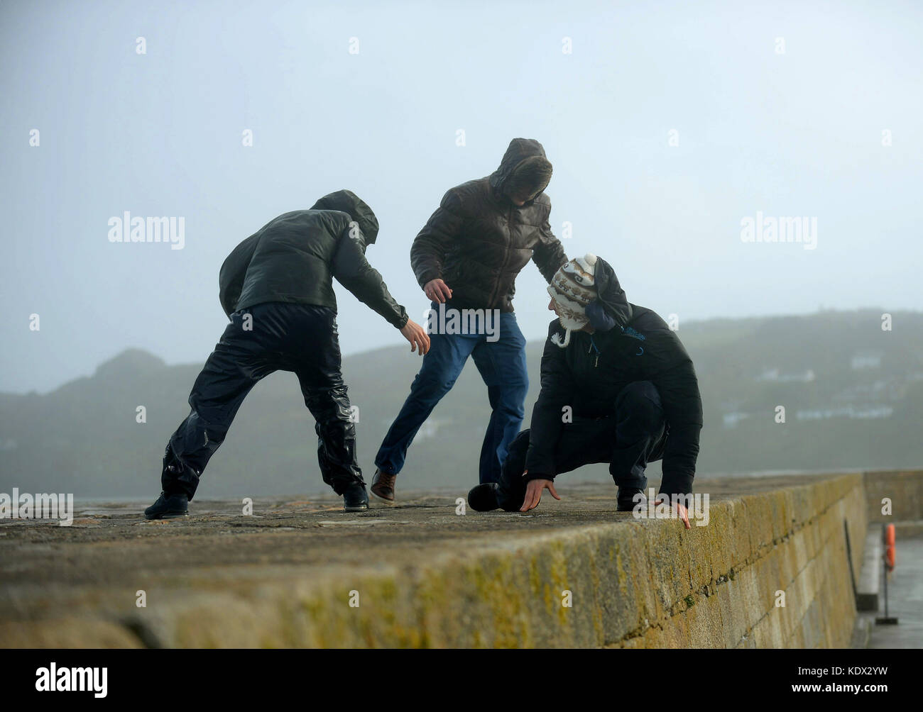 Men struggle to keep their footing amid gusts during storm Ophelia on ...