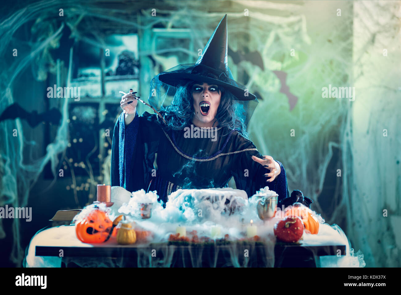 Witch with awfully face and hat on her head in creepy surroundings full ...