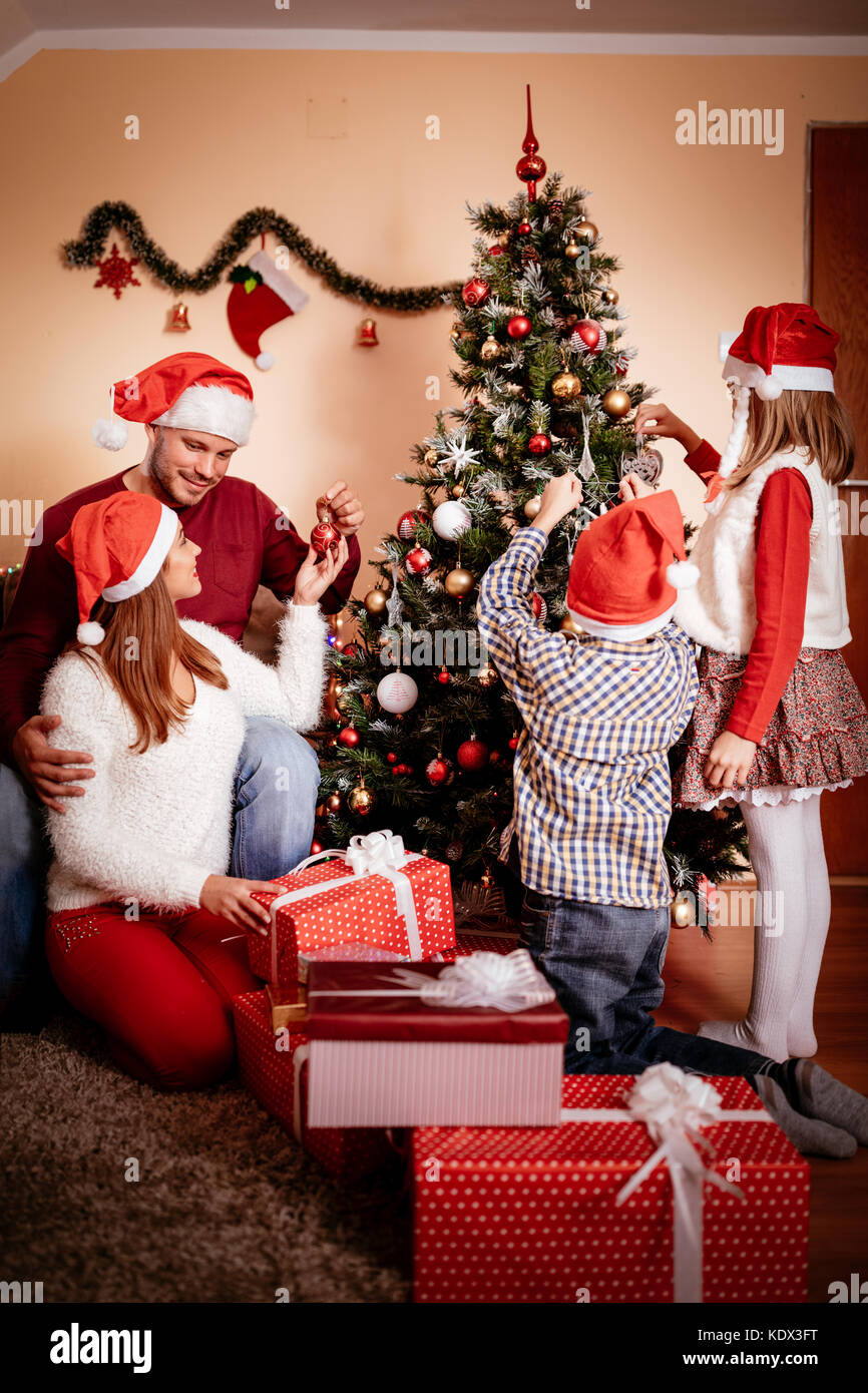 Beautiful happy parents decorating christmas tree with their children ...