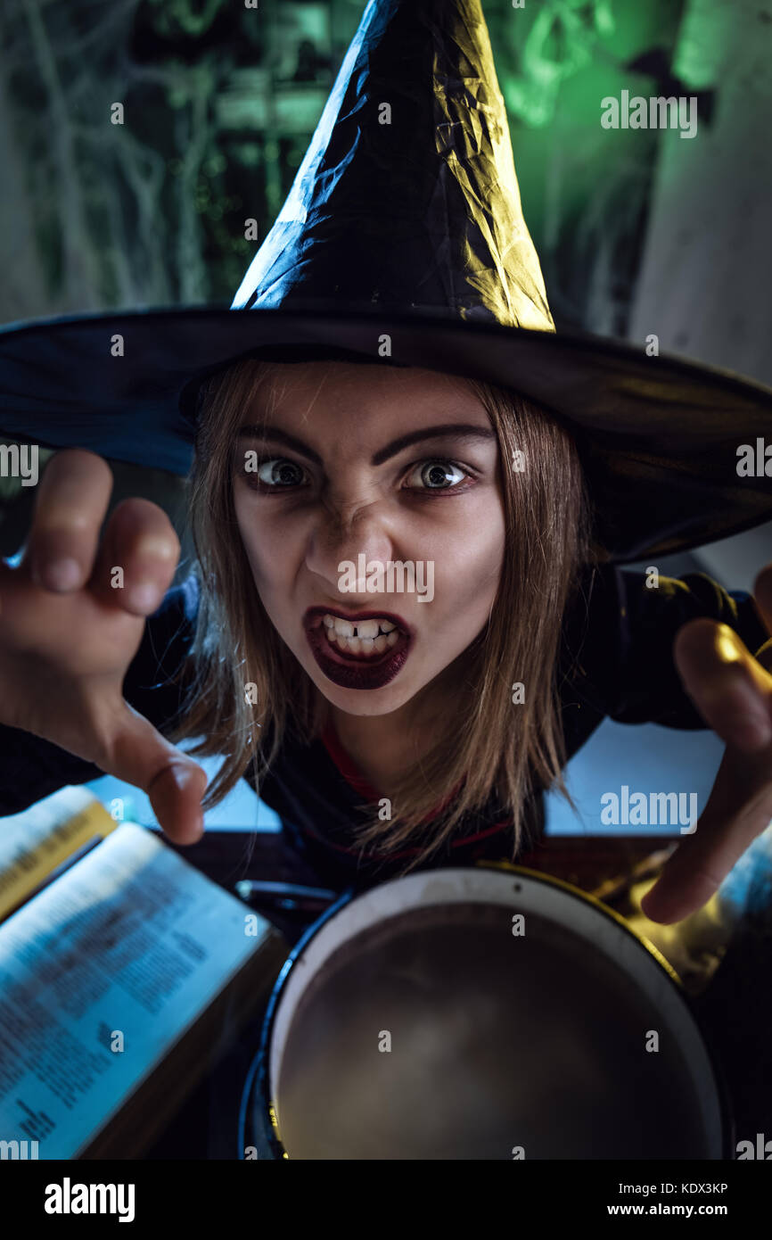 Close-up of young witch with awfully face looking at camera and tells ...