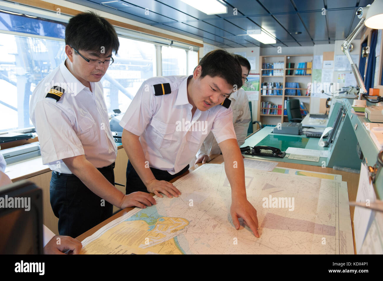 Captain and officers discuss navigation plans on board a merchant ship ...