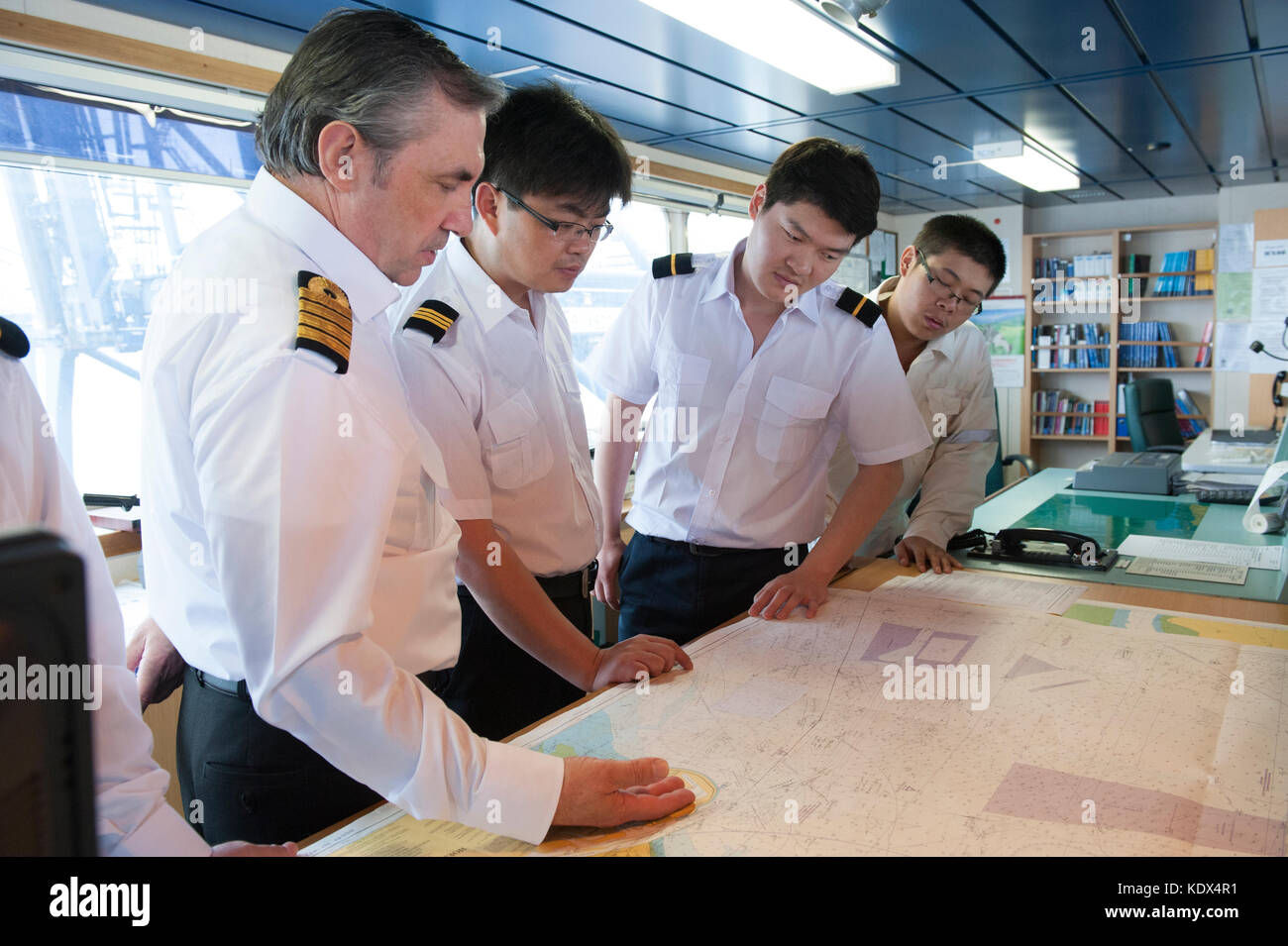 Captain and officers discuss navigation plans on board a merchant ship ...