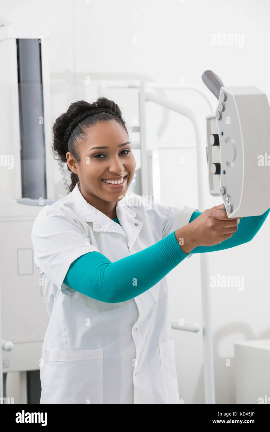Portrait of young female radiologist operating X-ray machine in ...