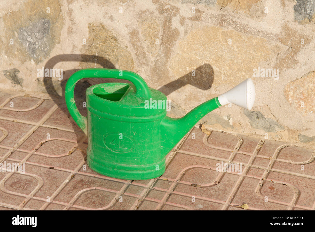 Green watering can on tiles in the sunshine Stock Photo - Alamy