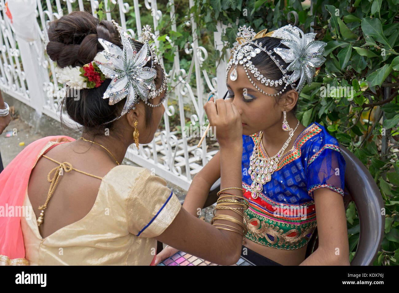 A Guyanese teenager fixing the hair and makeup of a young Guyanese girl ...