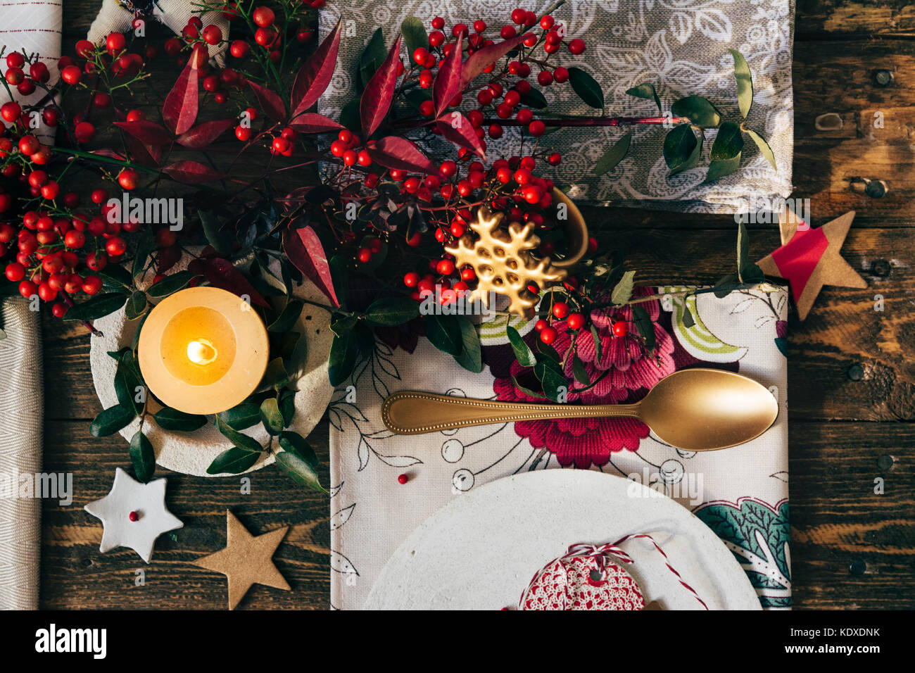 Candle lit on the Christmas table, surrounded by festive decoration, on ...