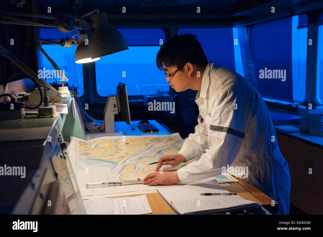 Navigation officer on a merchant ship plotting a course at night Stock ...