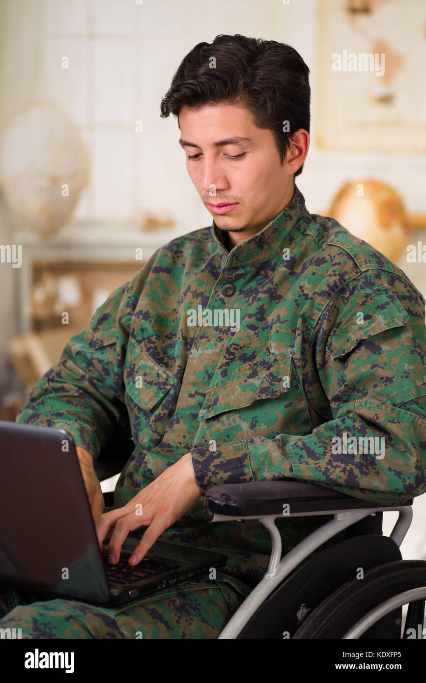 Close up of a handsome young soldier sitting on wheel chair using his ...