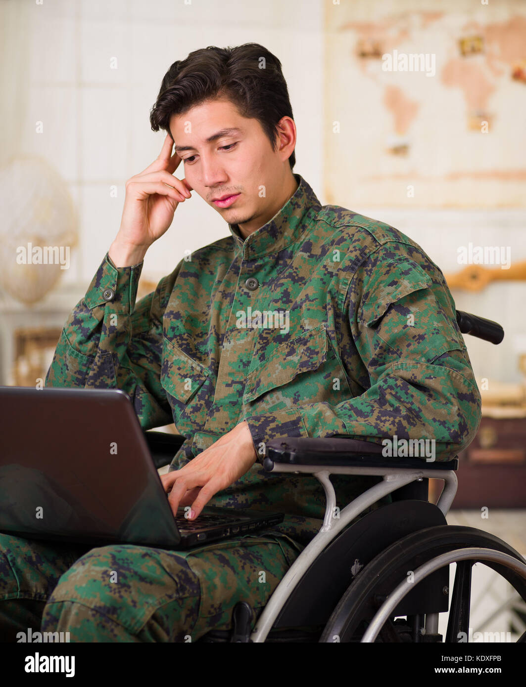 Close up of a thoughtful young soldier sitting on wheel chair using his ...