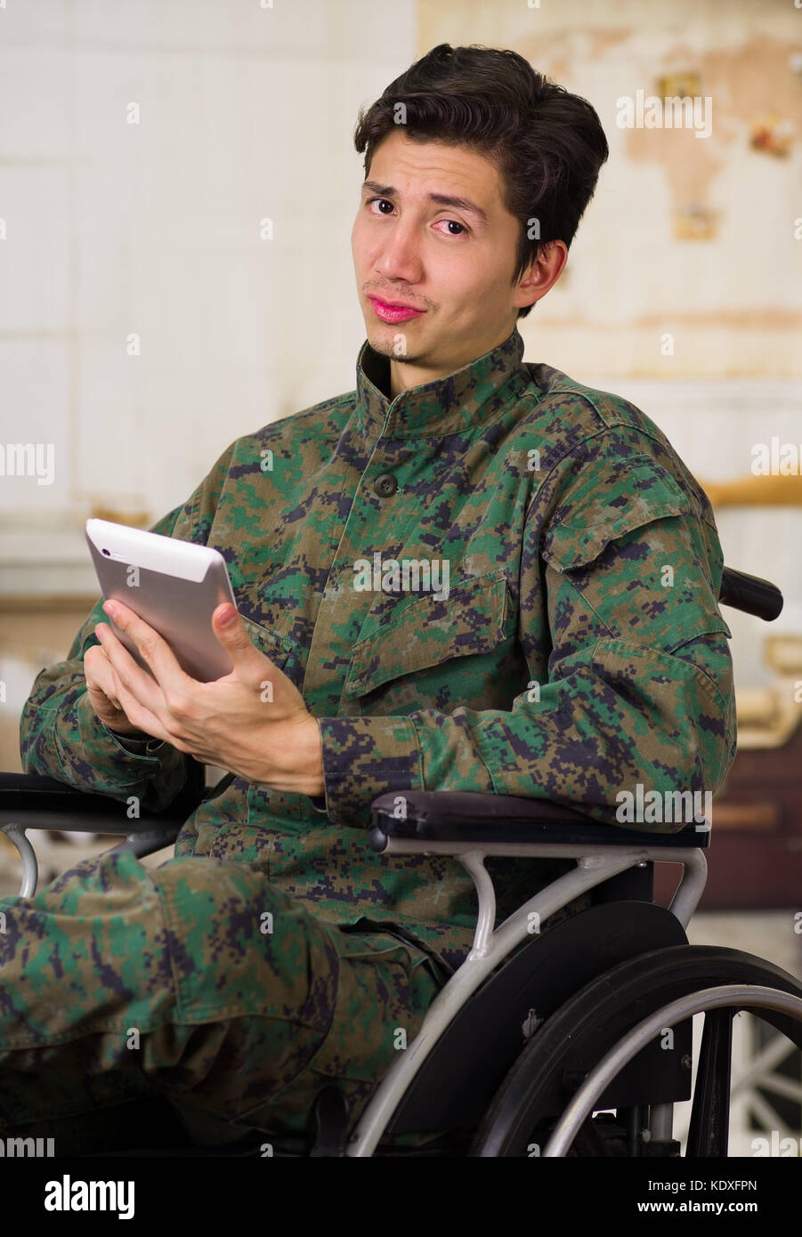 Close up of a handsome young soldier sitting on wheel chair using his ...