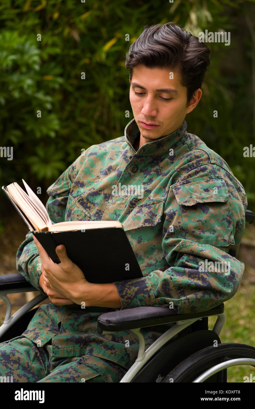 Close up of a handsome young soldier sitting on wheel chair reading a ...