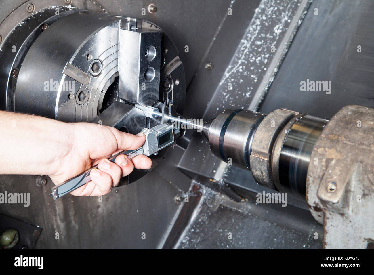 Operator measuring drilled parts out of turning machine Stock Photo - Alamy