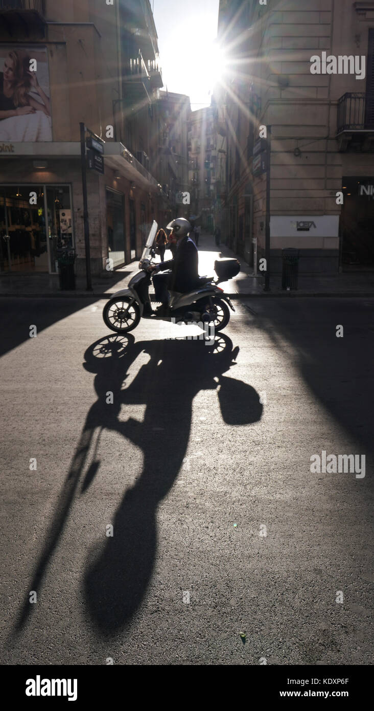 A man riding a moped at sunset in Palermo. From a series of travel ...