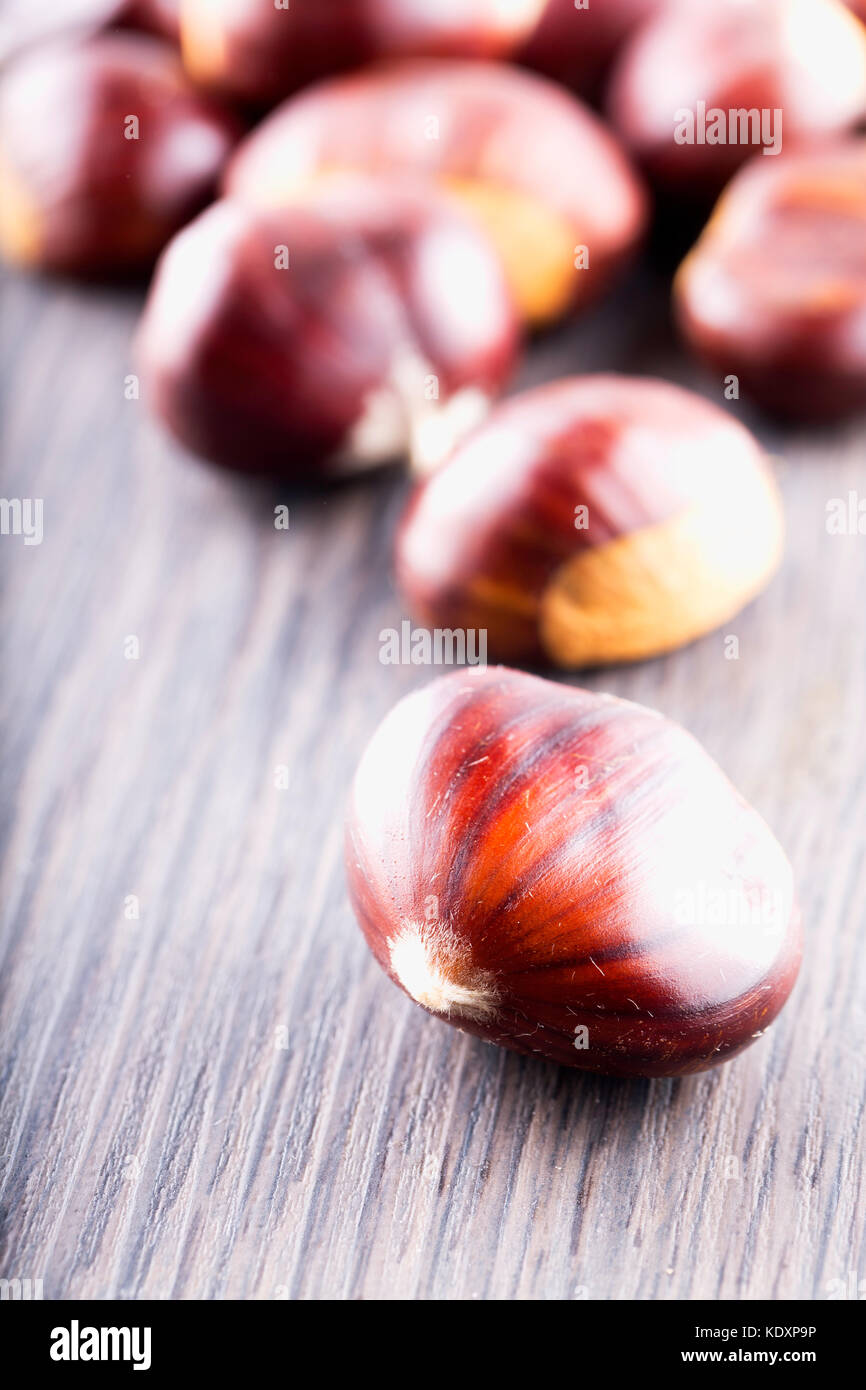 Chestnut in close up, over wooden table, vertical image Stock Photo - Alamy