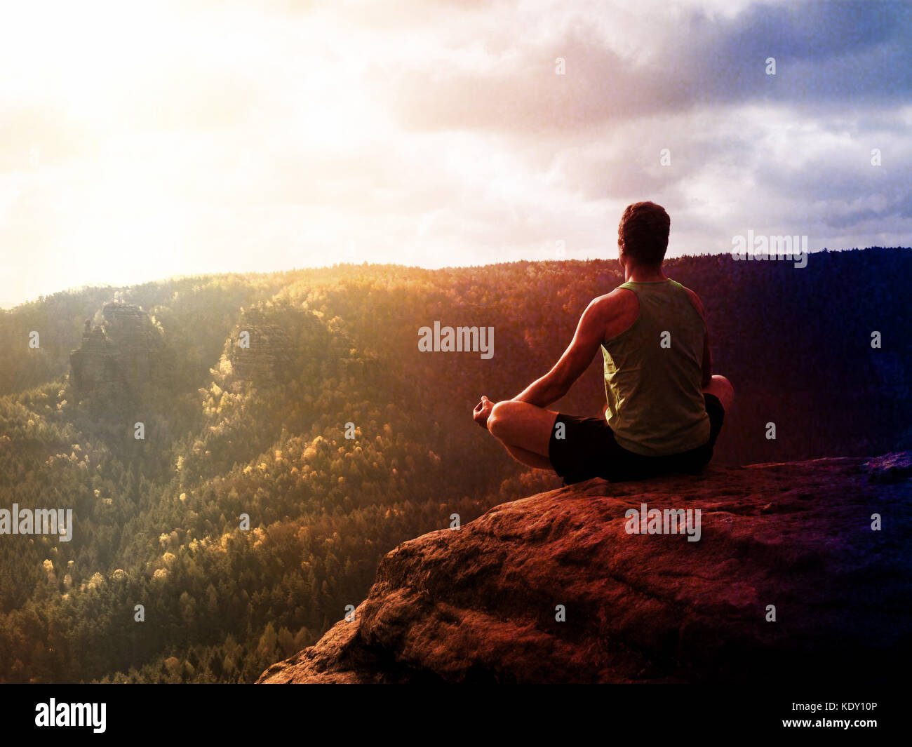 Lens defect. Man meditating in Lotus Pose on rocky cliff. Sportsman ...