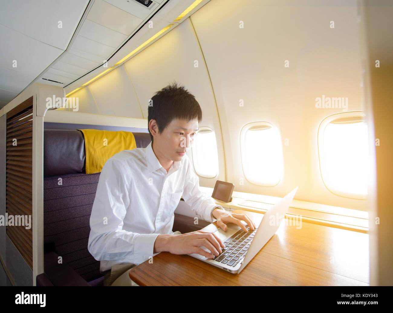 Asian man using laptop on luxury airplane Stock Photo - Alamy