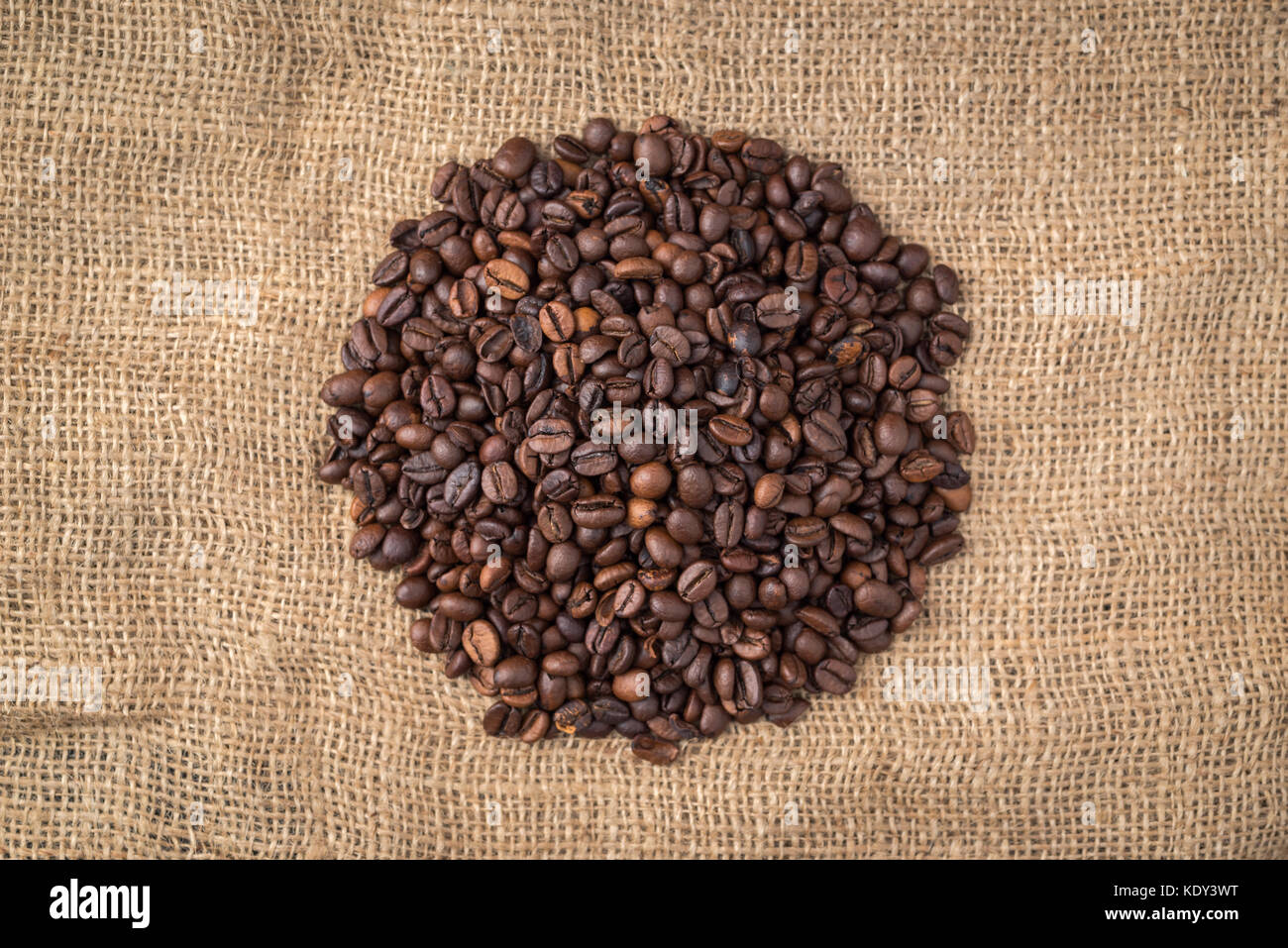 Pile of coffee beans in the middle on jute background Stock Photo - Alamy