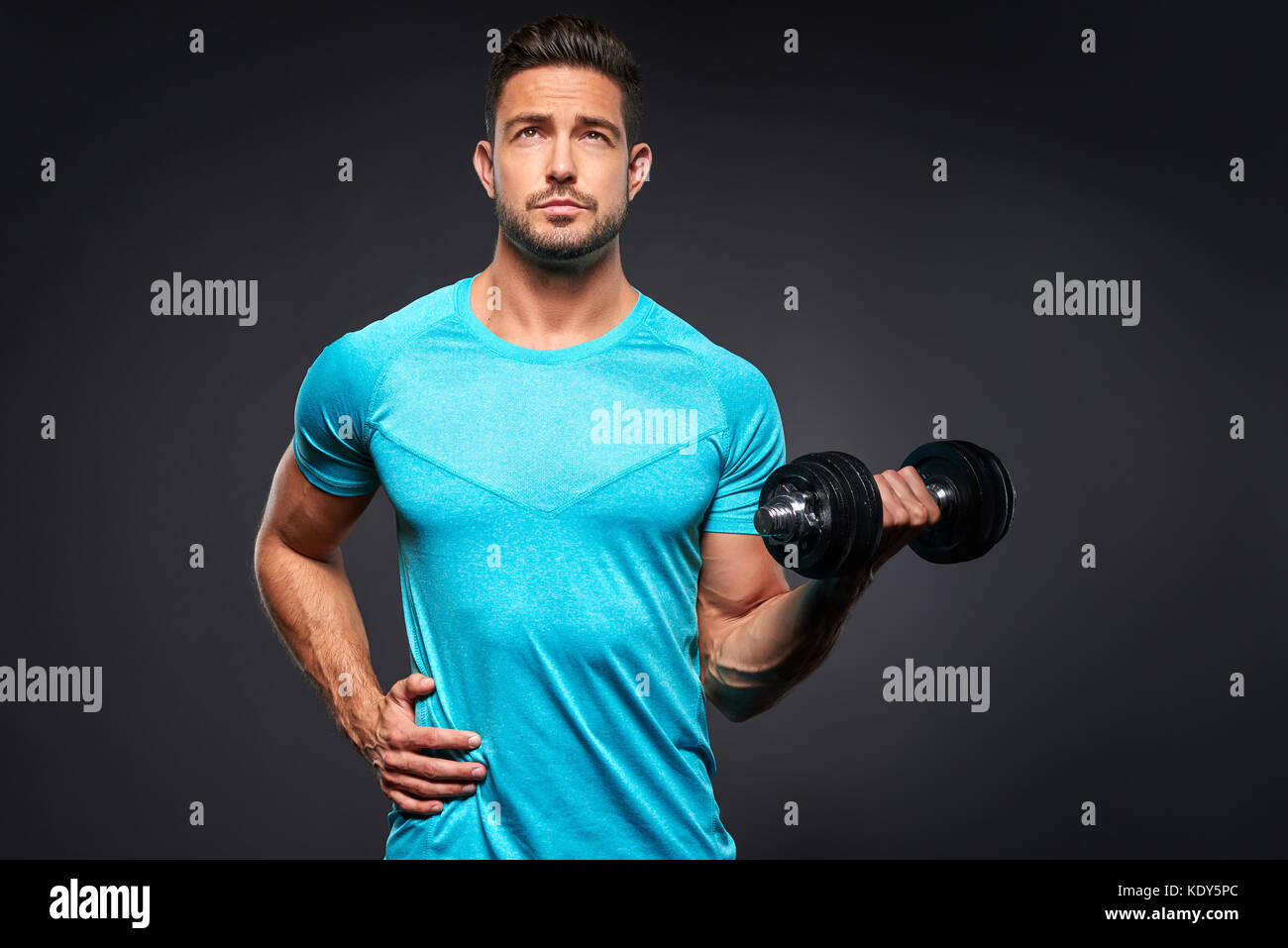 A handsome young sportsman lifting a dumbbell with one hand Stock Photo ...