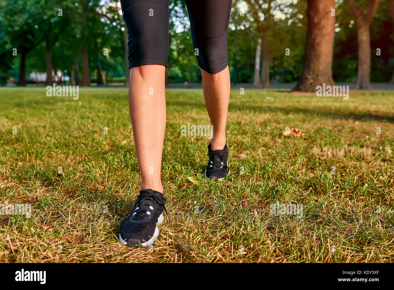 Close up of the legs of a young woman who is running off road in a park ...