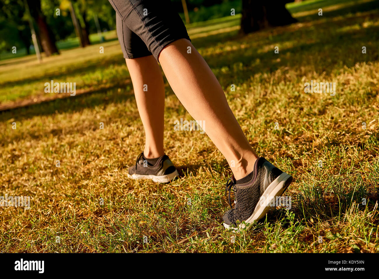 Close up of the legs of a young woman who is running off road in a park ...