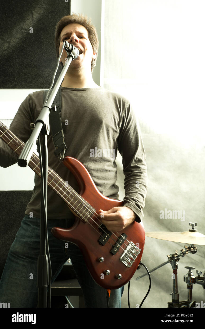 A Rock musician playing passionately bass in the rehearsal Studio Stock ...