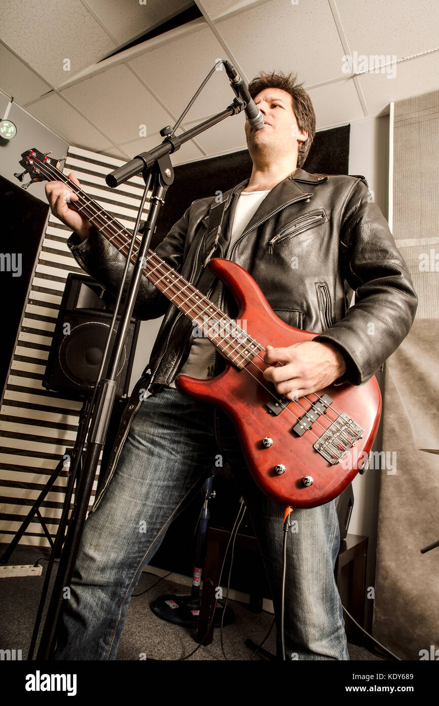A Rock musician playing passionately bass in the rehearsal Studio Stock ...