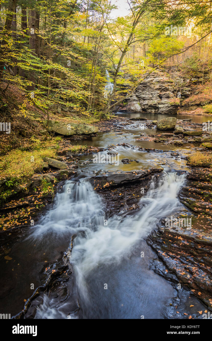 Waterfalls flow smoothly over rocks surrounded by peak fall foliage in ...