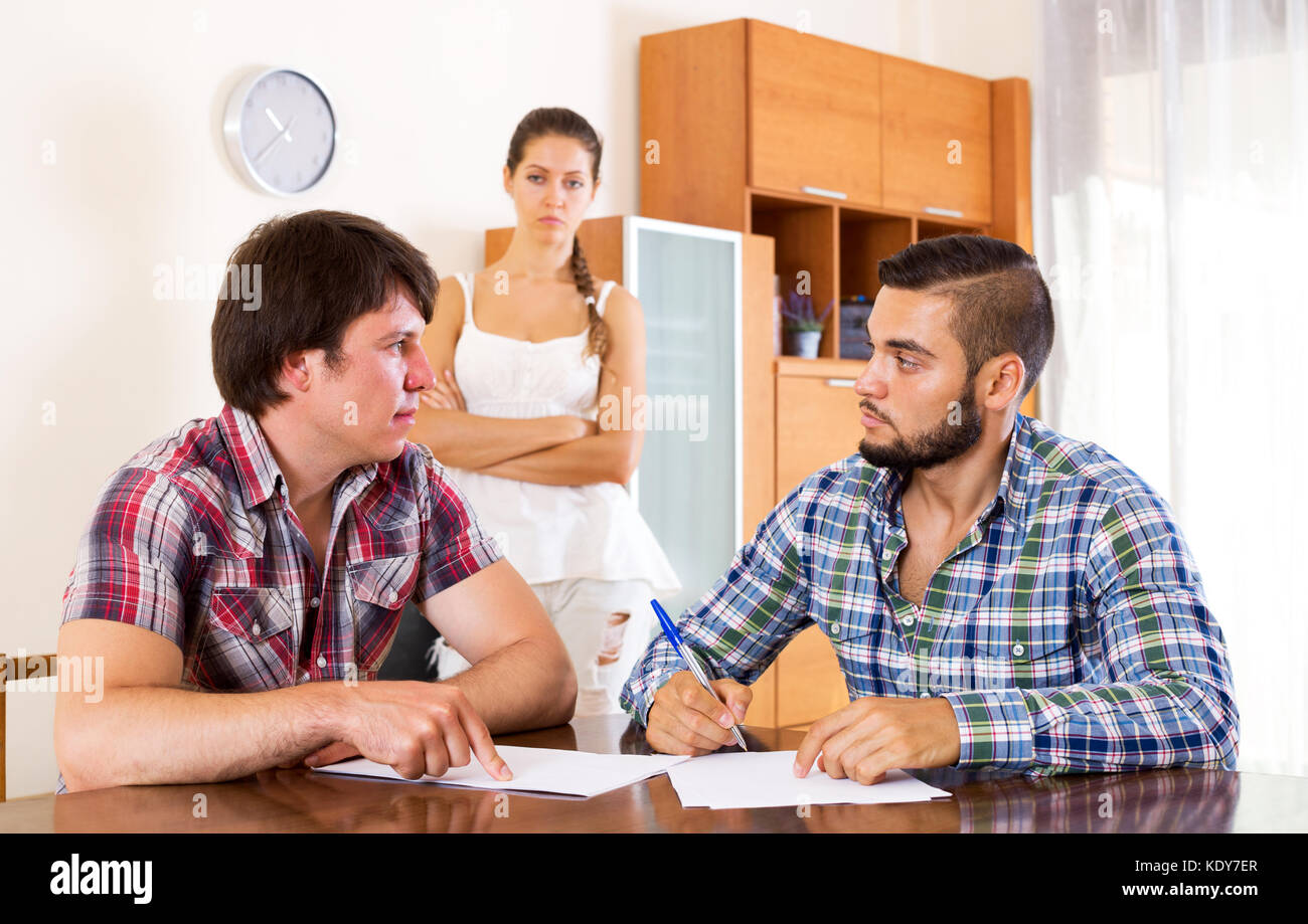 Two serious men and woman near desk with official papers Stock Photo ...