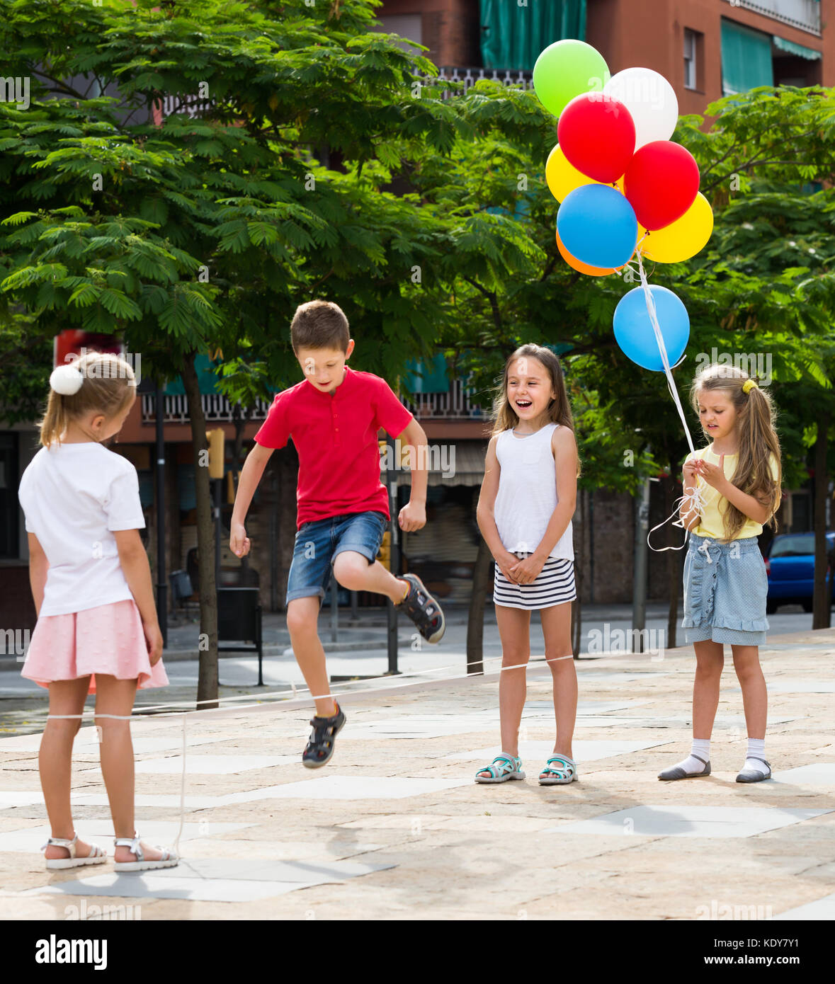 Small kids in school age playing together with chinese jumping rope ...