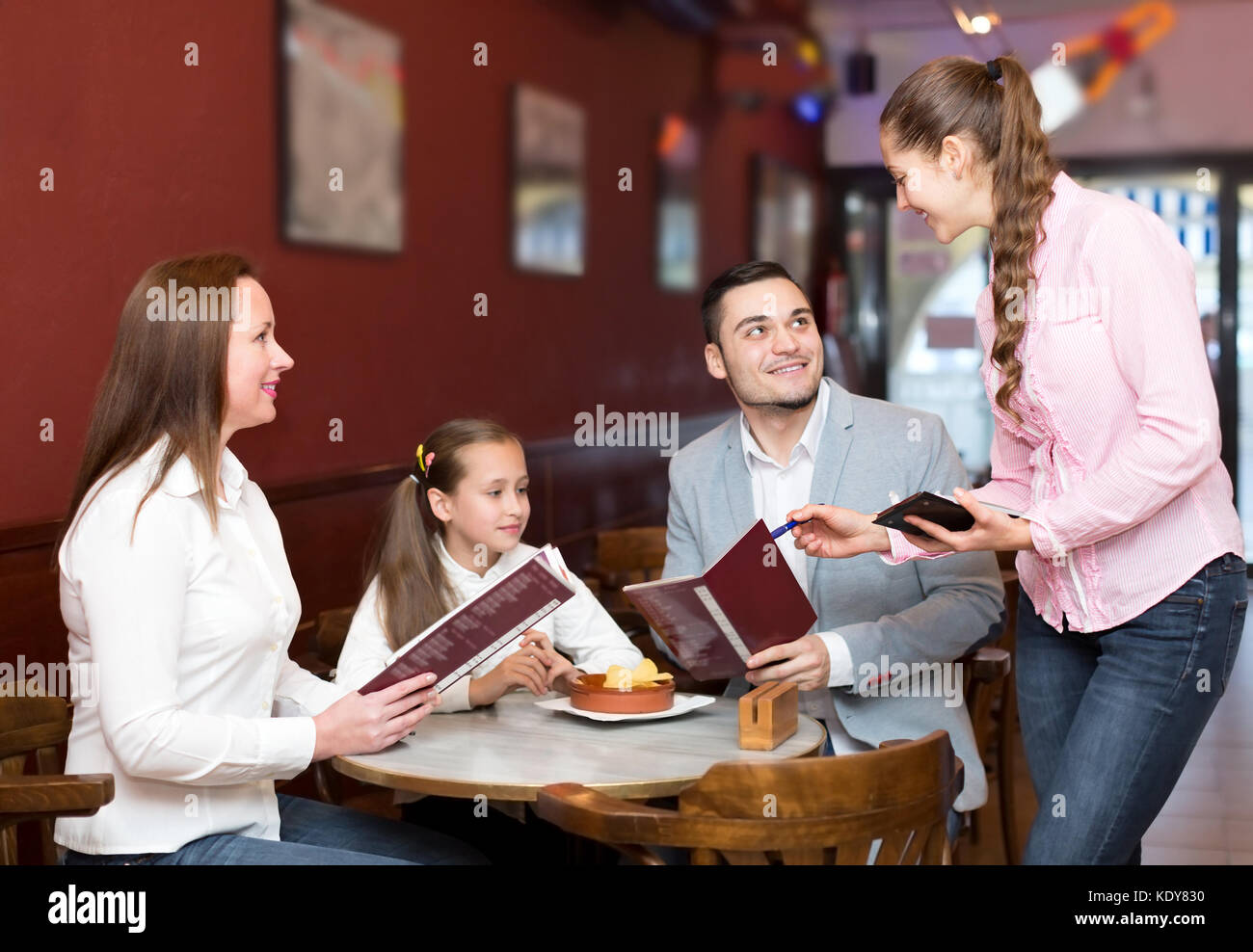 smiling waitress and happy family with child reading menu. Focus on the ...