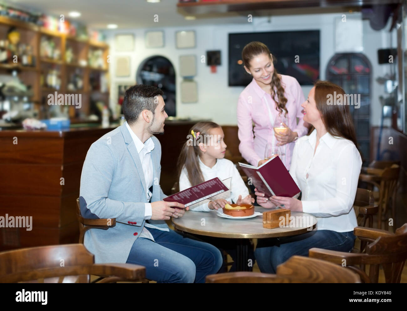 Young waitress and smiling family with child reading menu. Focus on the ...