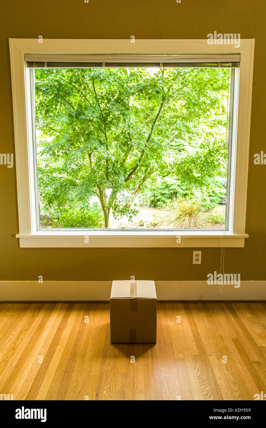 A small cardboard box below a large window in a residential home Stock ...