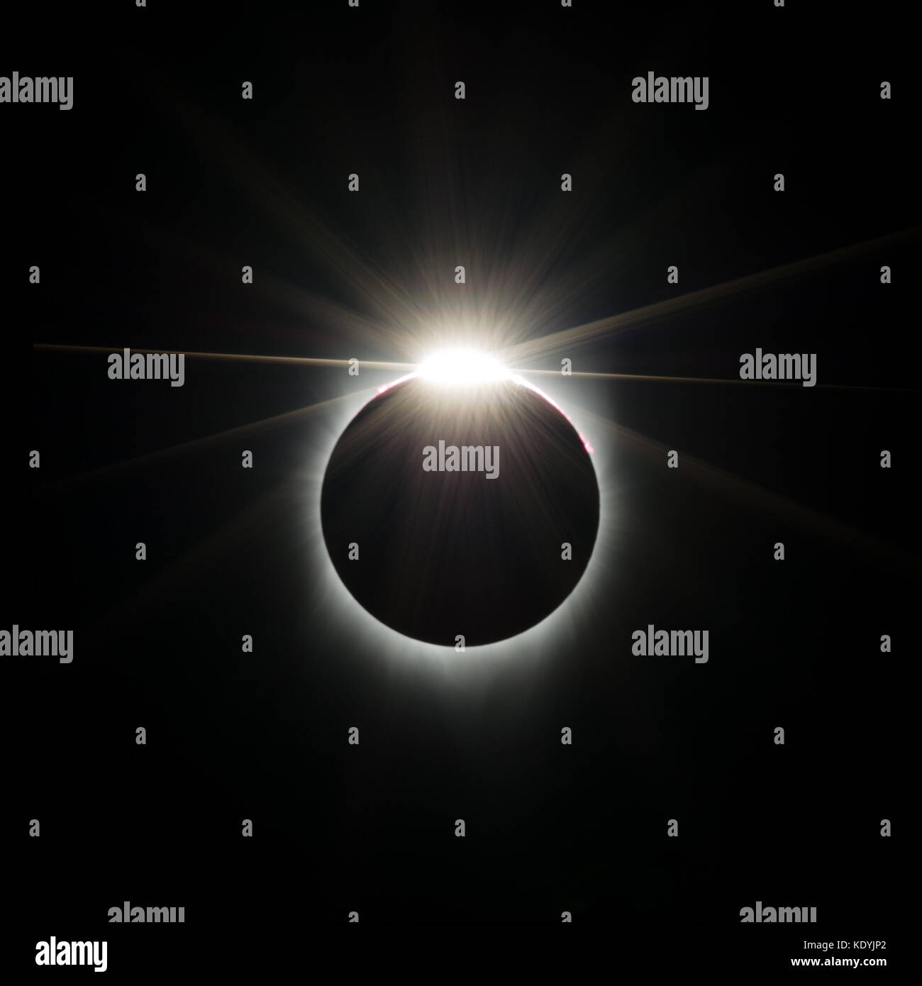 the sun begins to show from behind the moon in a solar eclipse creating ...