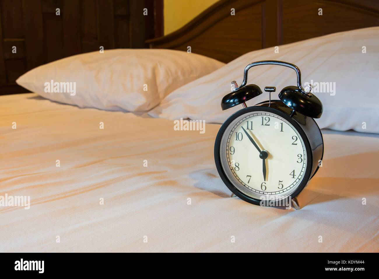 Analog alarm clock is on white bed, time in the morning Stock Photo - Alamy
