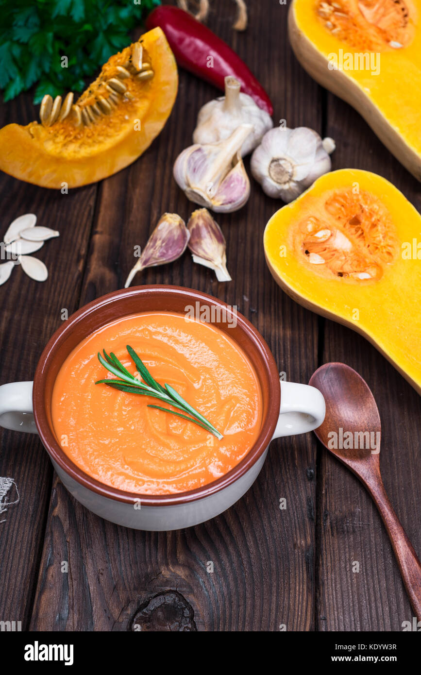 thick pumpkin soup in a ceramic plate on a brown wooden table, behind a ...